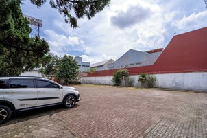 Um SUV branco estacionado em área pavimentada, com um prédio vermelho ao fundo.