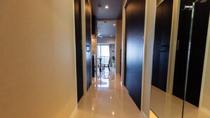 Um corredor moderno com piso brilhante, que leva a uma sala de jantar com mesa e cadeiras.