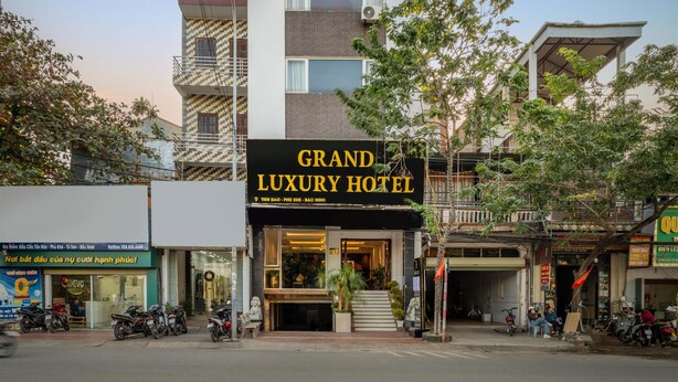 Um hotel com uma placa grande, uma escadaria que leva à entrada e várias motocicletas estacionadas.