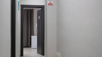 Um corredor com piso em padrão herringbone, uma porta no final e um quadro na parede.