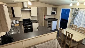 Uma cozinha compacta equipada com fogão, micro-ondas e frigorífico.