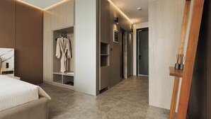 Quarto de hotel moderno com cama, guarda-roupa embutido e aparador de madeira.