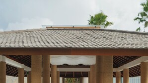 Uma galeria coberta com telhado de azulejos, colunas de madeira e guarda-corpos de corda.