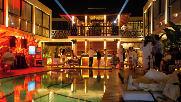 Área de piscina com bar e espreguiçadeiras.
