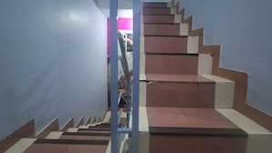 Escada com degraus alternados em vermelho e bege, que levam a um patamar.
