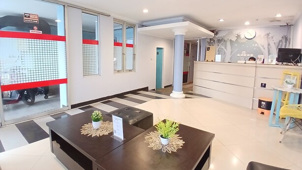 Uma área de recepção com balcão de check-in, espaço de espera com mesinha de centro e um balcão de atendimento.