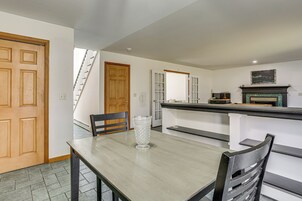 Uma sala de jantar com uma mesa de madeira, cadeiras e um vaso de vidro transparente.