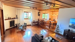 Uma sala de estar ampla com lareira, área de jantar e cozinha.