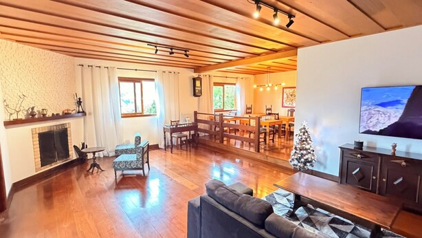 Uma sala de estar ampla com lareira, uma mesa de jantar e uma televisão.