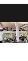 Um espaço interior moderno com várias áreas de estar, incluindo mesas redondas e cadeiras, e um candelabro decorativo.