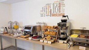 Buffet com diversos tipos de comida e uma máquina de café.