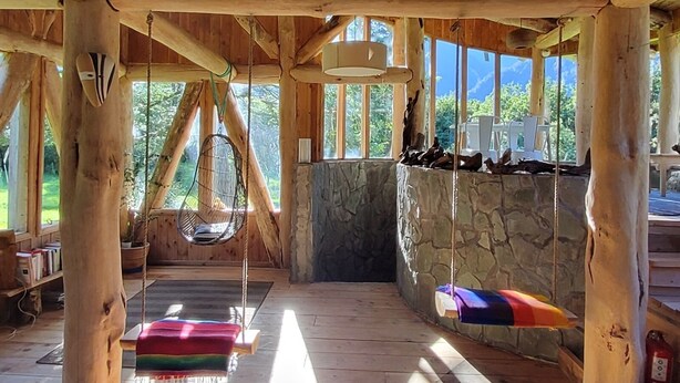Uma cabana de madeira espaçosa, com teto alto, janelas amplas e luminária pendente.