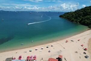 Uma praia com águas cristalinas, barcos e guarda-sóis.