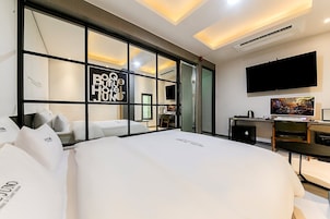 Quarto de hotel moderno com uma cama grande, uma escrivaninha com computador, televisão de tela plana e uma janela ampla com vista.