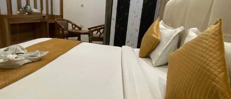 Quarto de hotel com uma cama grande, uma escrivaninha de madeira e uma cadeira.