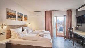 Quarto de hotel com cama, escrivaninha e vista para a cidade.