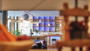 Uma área de bar com prateleiras de garrafas, balcão e assentos.