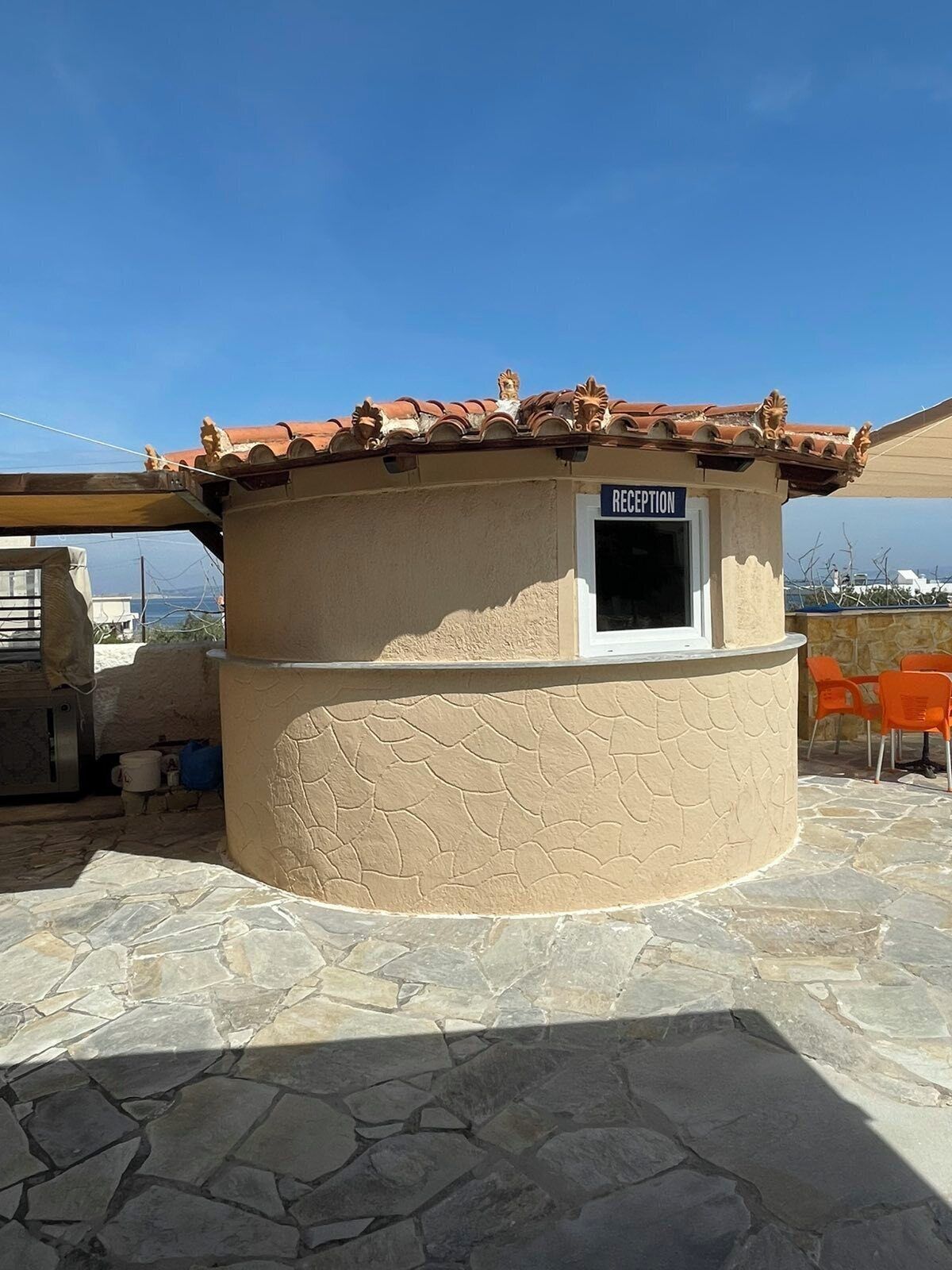 Uma área de recepção com telhado de azulejos, uma janela e uma parede de pedra.