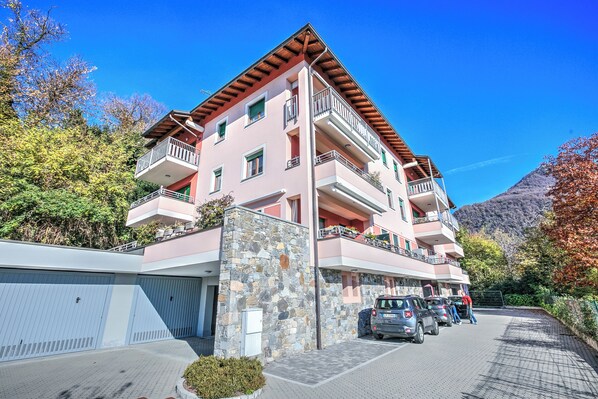 Um hotel de vários andares com varandas, fachada de pedra e área de estacionamento.