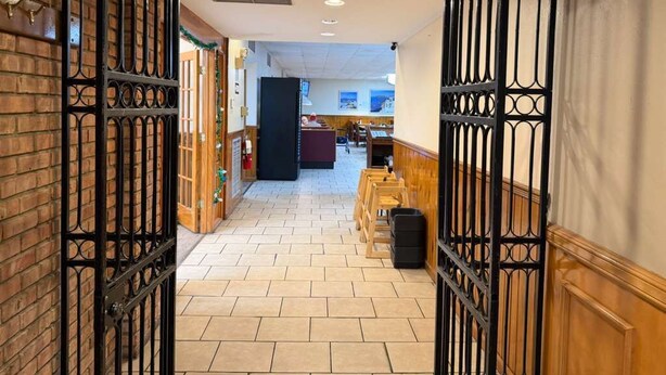Um corredor com piso de azulejos que leva a uma área de estar com bancos de madeira e um balcão.