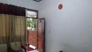 Quarto com cama, cadeira, porta e janela.
