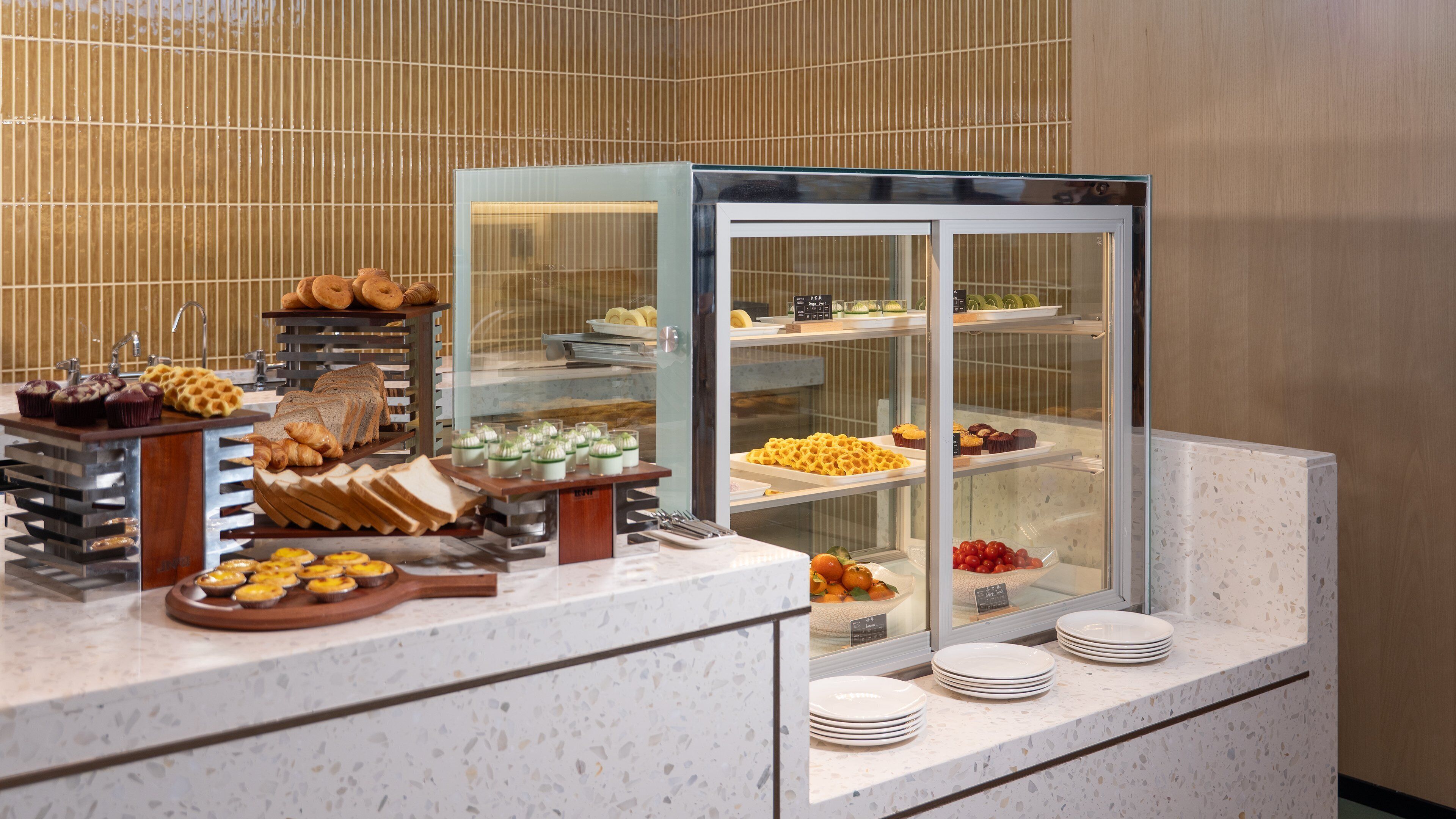 Buffet com diversos itens de comida, incluindo doces, pães e frutas.