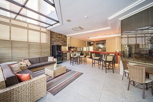 Uma sala de estar ampla com sofá, cadeiras, uma mesa de centro e um espaço de cozinha com bancada e cadeiras.