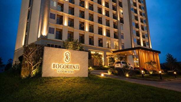 Um hotel de vários andares com uma entrada imponente, uma placa de identificação e fachada bem iluminada.