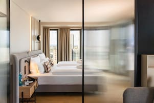 Quarto de hotel com uma cama grande, uma escrivaninha e vista para a cidade.