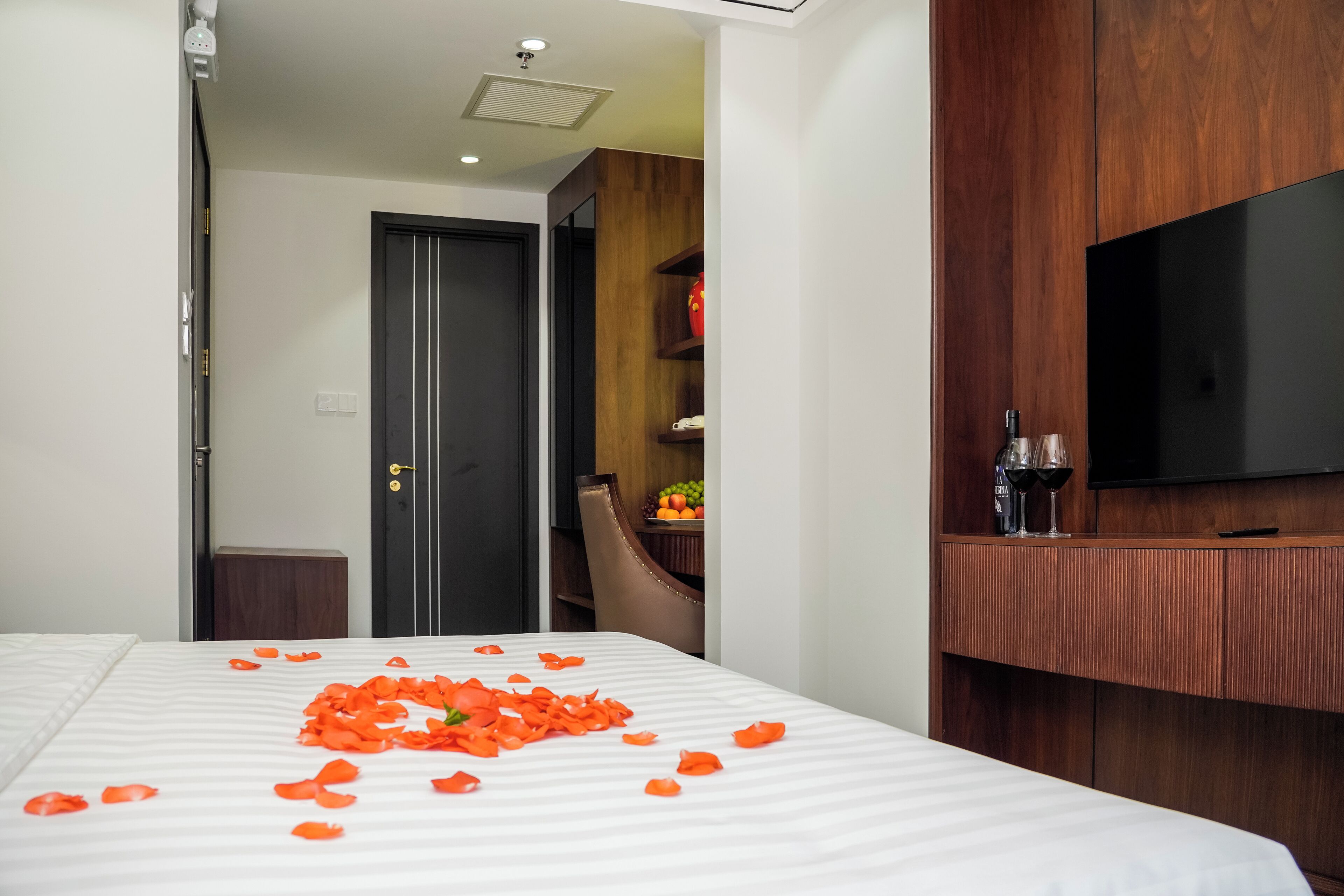 Quarto de hotel com uma cama, televisão, armário de madeira e uma porta.