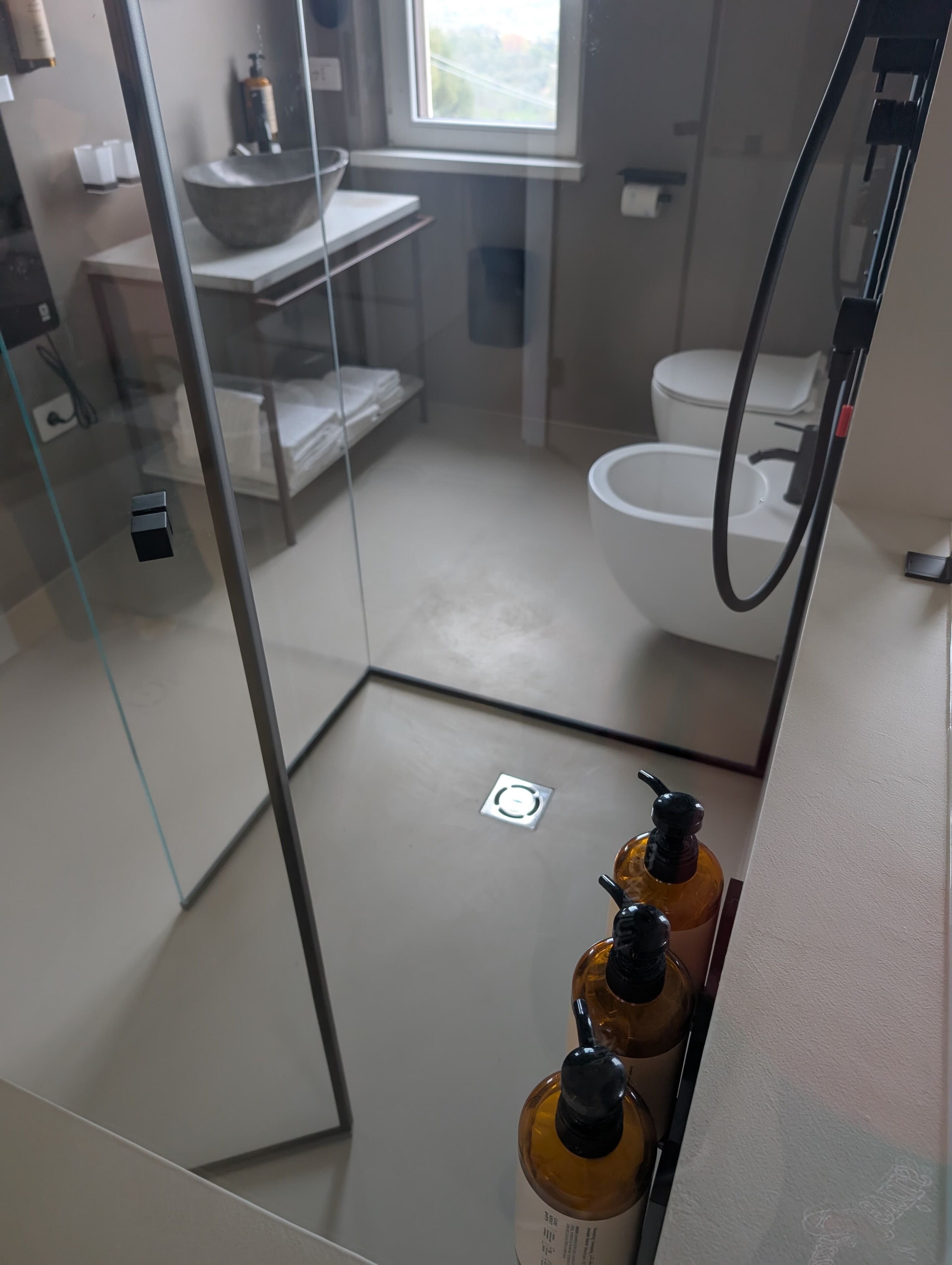 Um banheiro moderno com chuveiro de vidro, vaso sanitário e pia.
