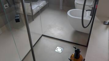 Um banheiro moderno com chuveiro de vidro, vaso sanitário e pia.