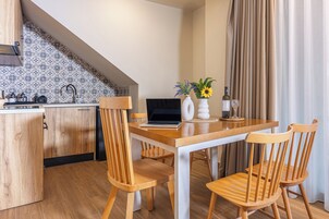 Uma cozinha moderna com armários de madeira, um laptop sobre a mesa de jantar e um vaso com flores.