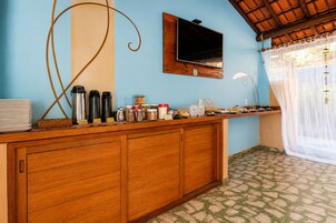 Um quarto com um balcão de madeira, uma televisão presa na parede e uma janela com cortina.