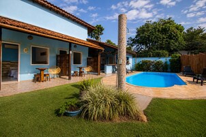 Um imóvel residencial com piscina, área de estar externa e gramado bem cuidado.