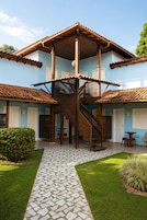 Um edifício com escadaria central, várias portas e um pátio com azulejos.