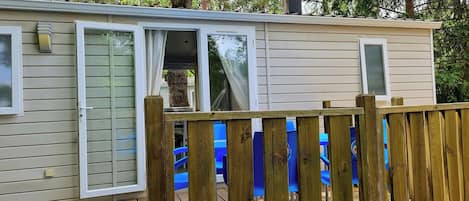 Uma cabana pequena com varanda, porta deslizante e chaminé.