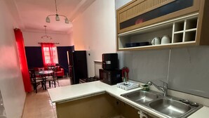 Uma cozinha compacta com pia embutida, micro-ondas e um espaço de jantar com mesa e cadeiras.