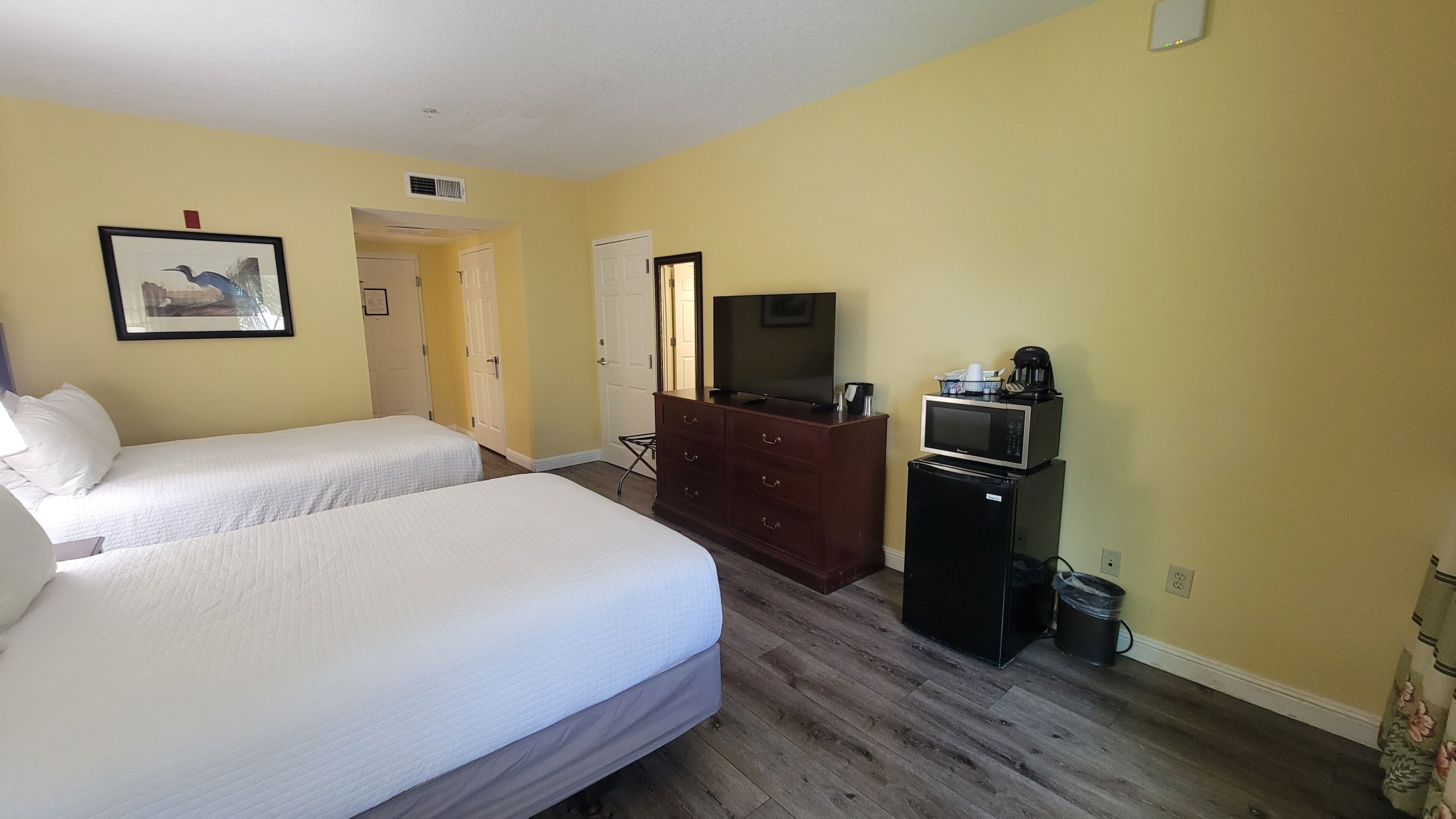 Quarto de hotel com duas camas, uma cômoda, uma televisão e um micro-ondas.