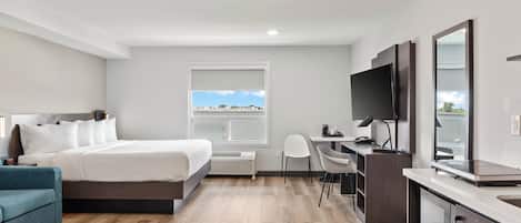 Quarto de hotel com cama, escrivaninha, cadeira, televisão e vista para o exterior.