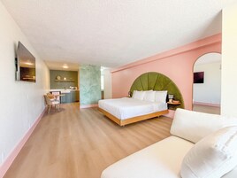 Um quarto moderno com cama, uma escrivaninha pequena e um espaço com cozinha compacta.