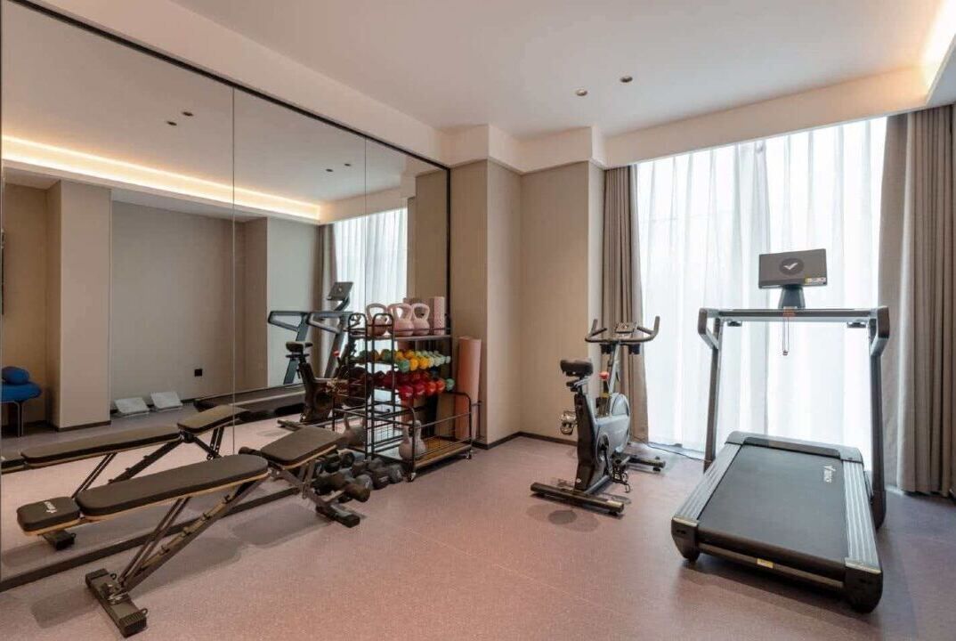 Quarto de hotel com área de ginásio, incluindo esteiras, pesos e equipamentos de exercício.