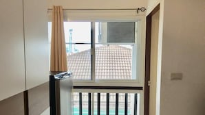 Corredor que dá para uma varanda com vista para um telhado em azulejos e uma piscina.