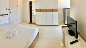 Quarto de hotel moderno com uma cama grande, televisão e armário.
