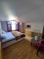 Quarto com cama, televisão, mesa pequena e cadeira.
