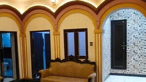 Um quarto amplo com um sofá grande, portas em arco e um lustre.