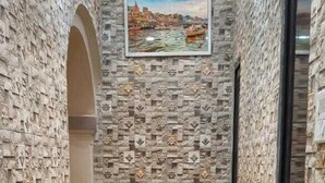 Um corredor com paredes de pedra e chão de mármore, que leva a uma porta.