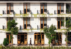 Um edifício com vários andares, varandas, móveis de madeira e vegetação.