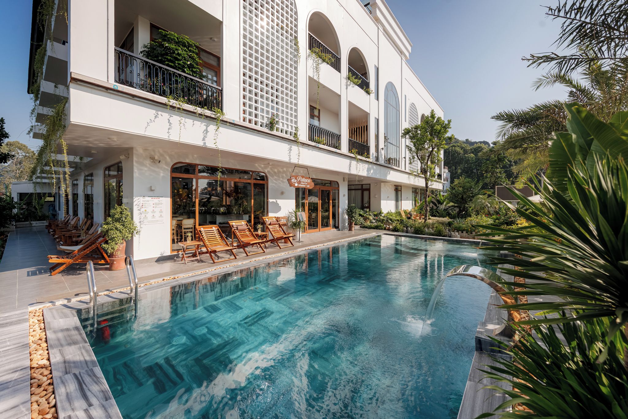 Um hotel moderno com piscina, área de estar externa e vegetação exuberante.
