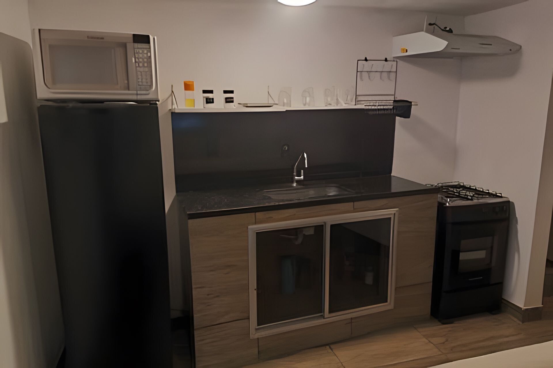 Cozinha compacta com micro-ondas, pia e fogão.